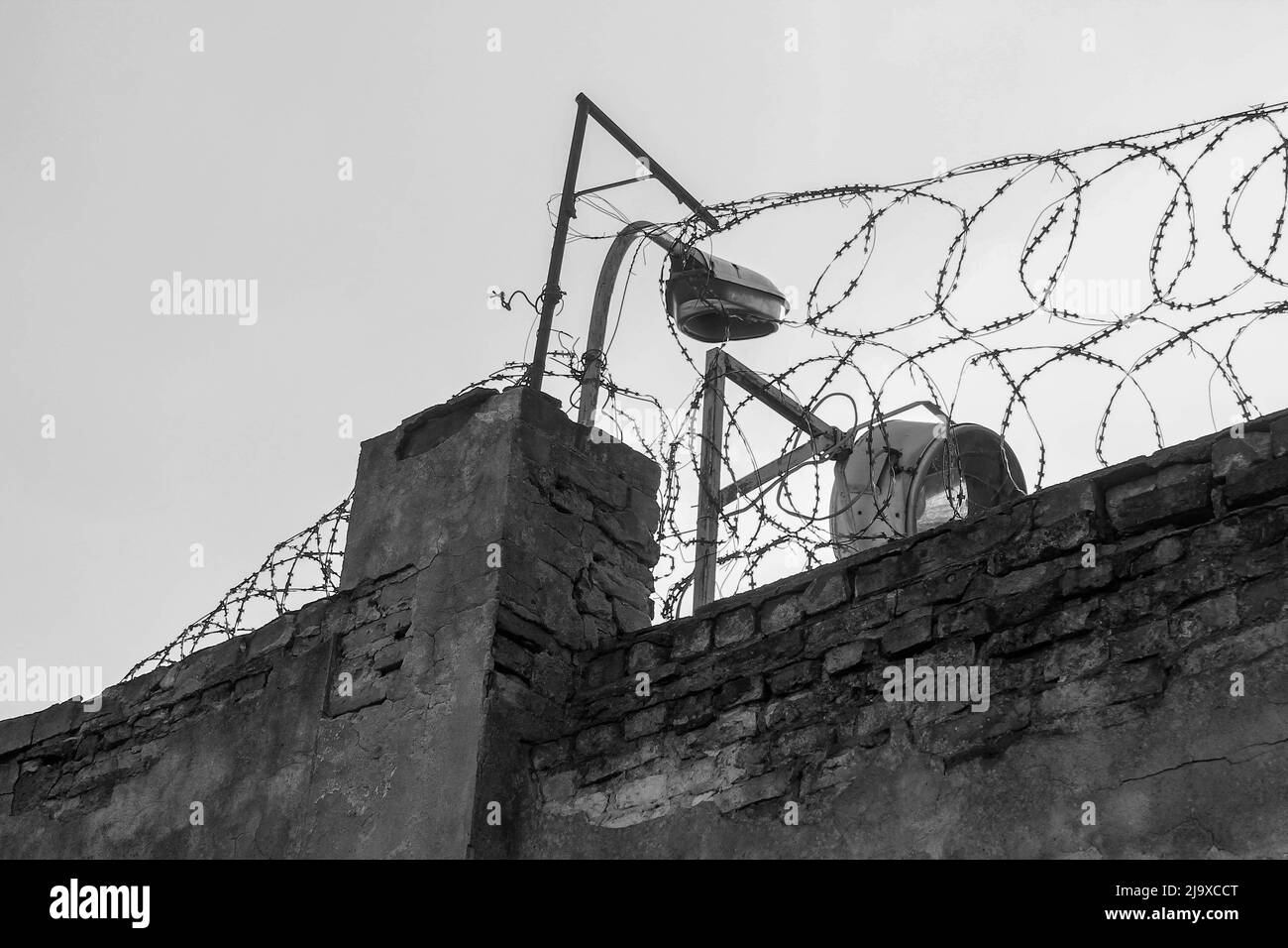 Prison wall with barbed wire and searchlight Stock Photo - Alamy