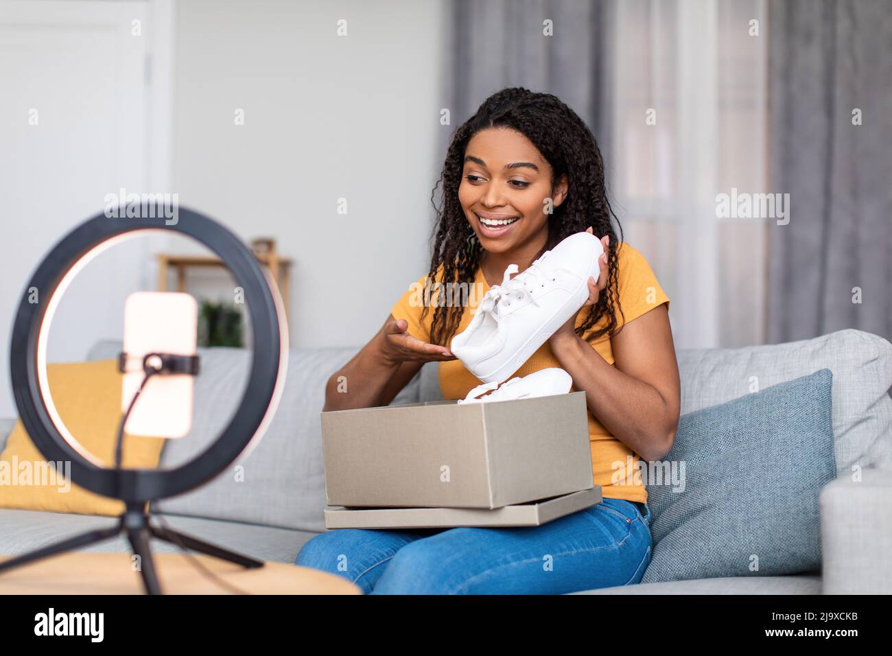 Unboxing video. Excited black female blogger recording content for her ...