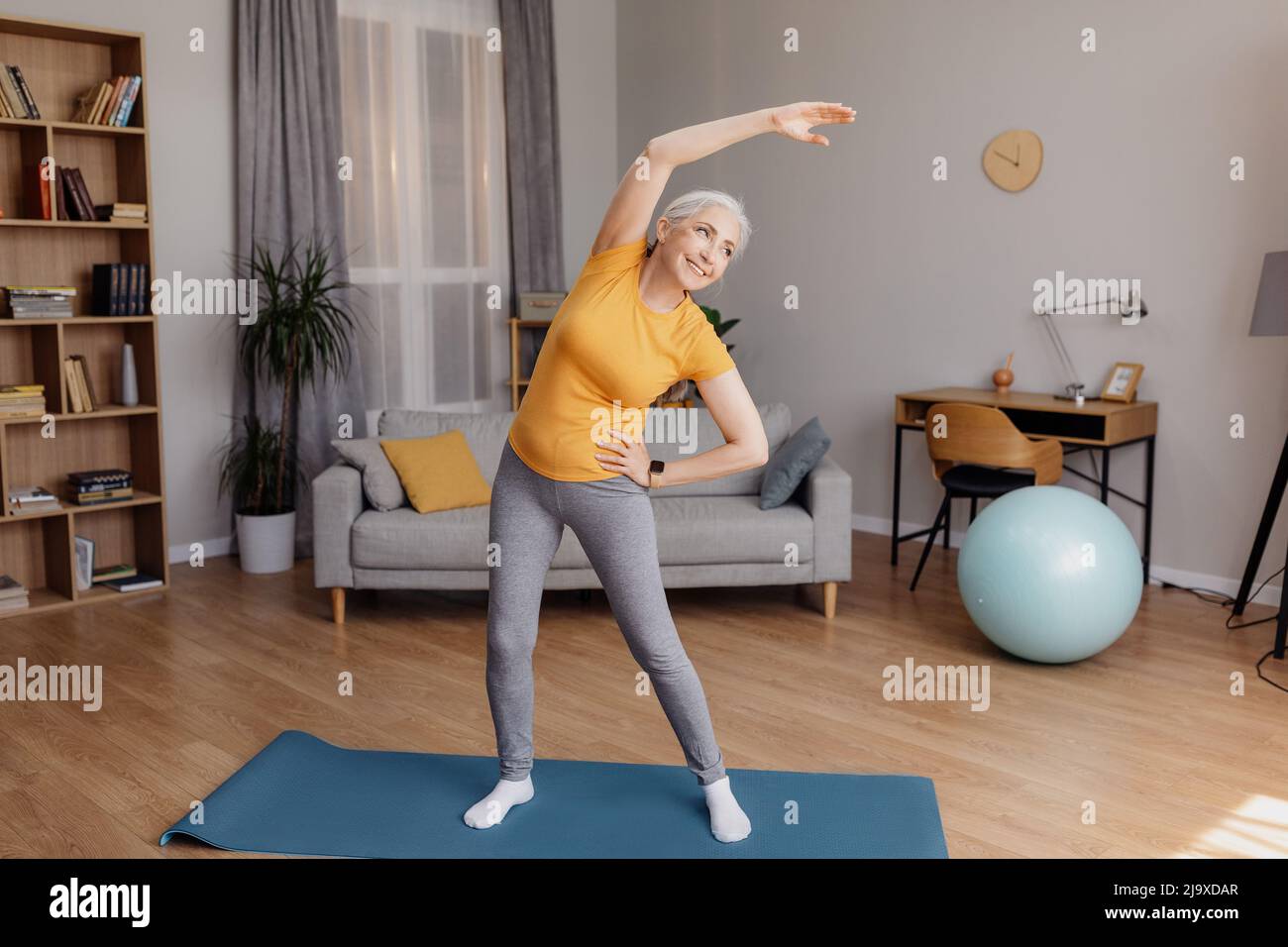 Sport on retirement. Happy senior woman doing flexibility exercises for ...