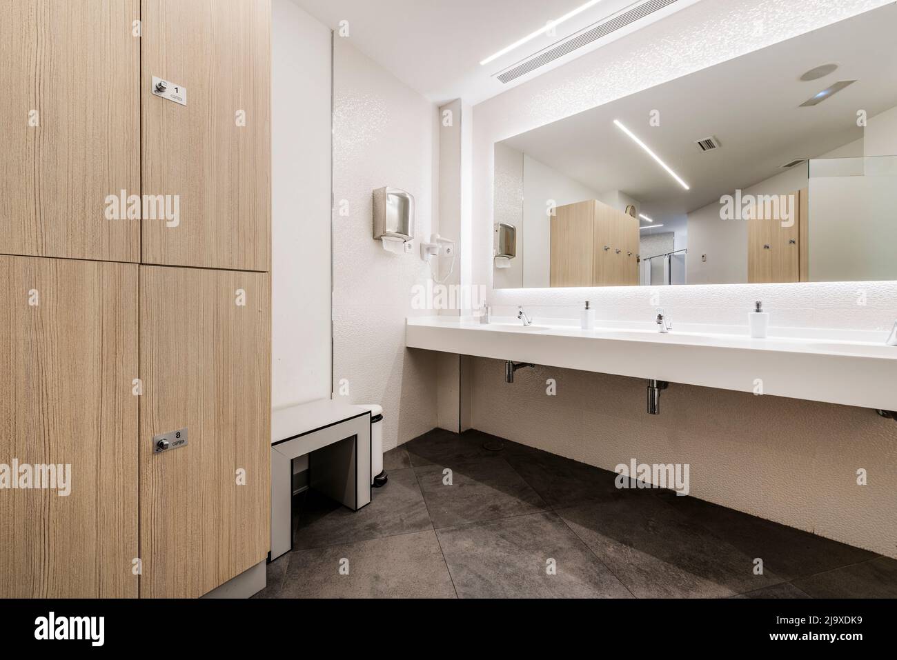 Restroom of a gym locker room with a wooden locker cabinet and a white ...