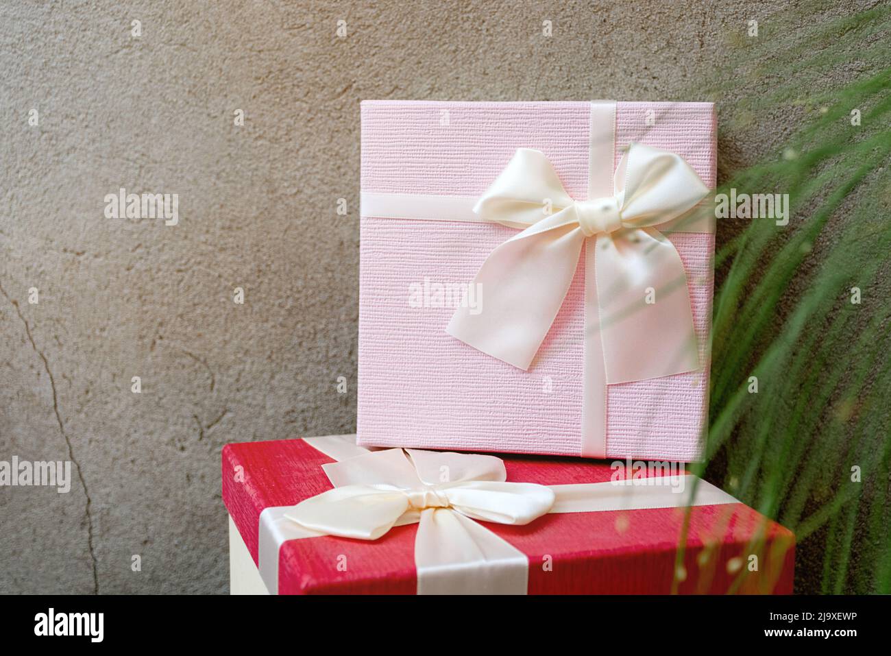 Front view of two beautiful gift boxes with satin ribbon on natural ...