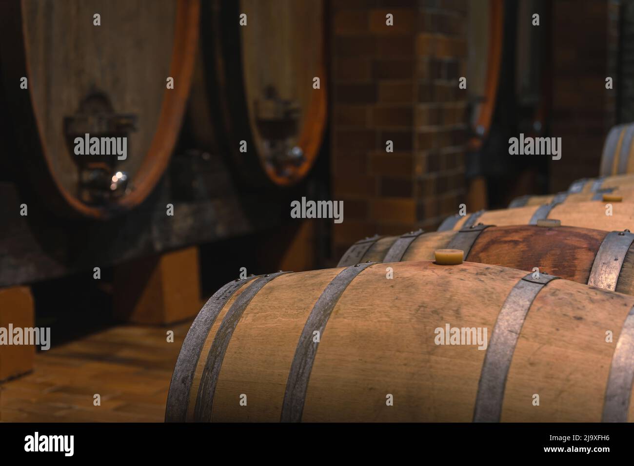 Rows of wooden wine-filled casks line the cellar of the winery, a wine ...