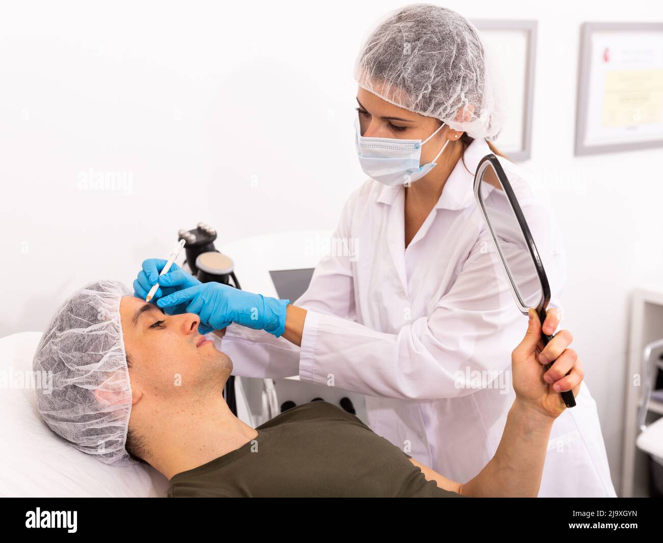 Woman beautician examining male face skin Stock Photo - Alamy