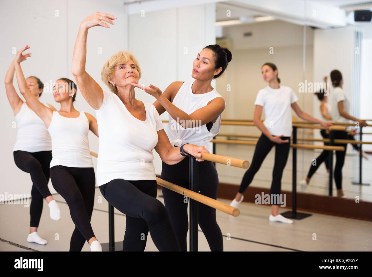 European woman performs an exercise near a ballet barre, where the ...