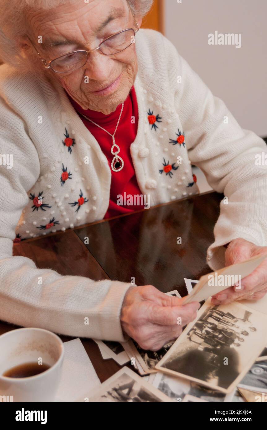 Elderly woman holding an old picture and reminiscing Stock Photo - Alamy