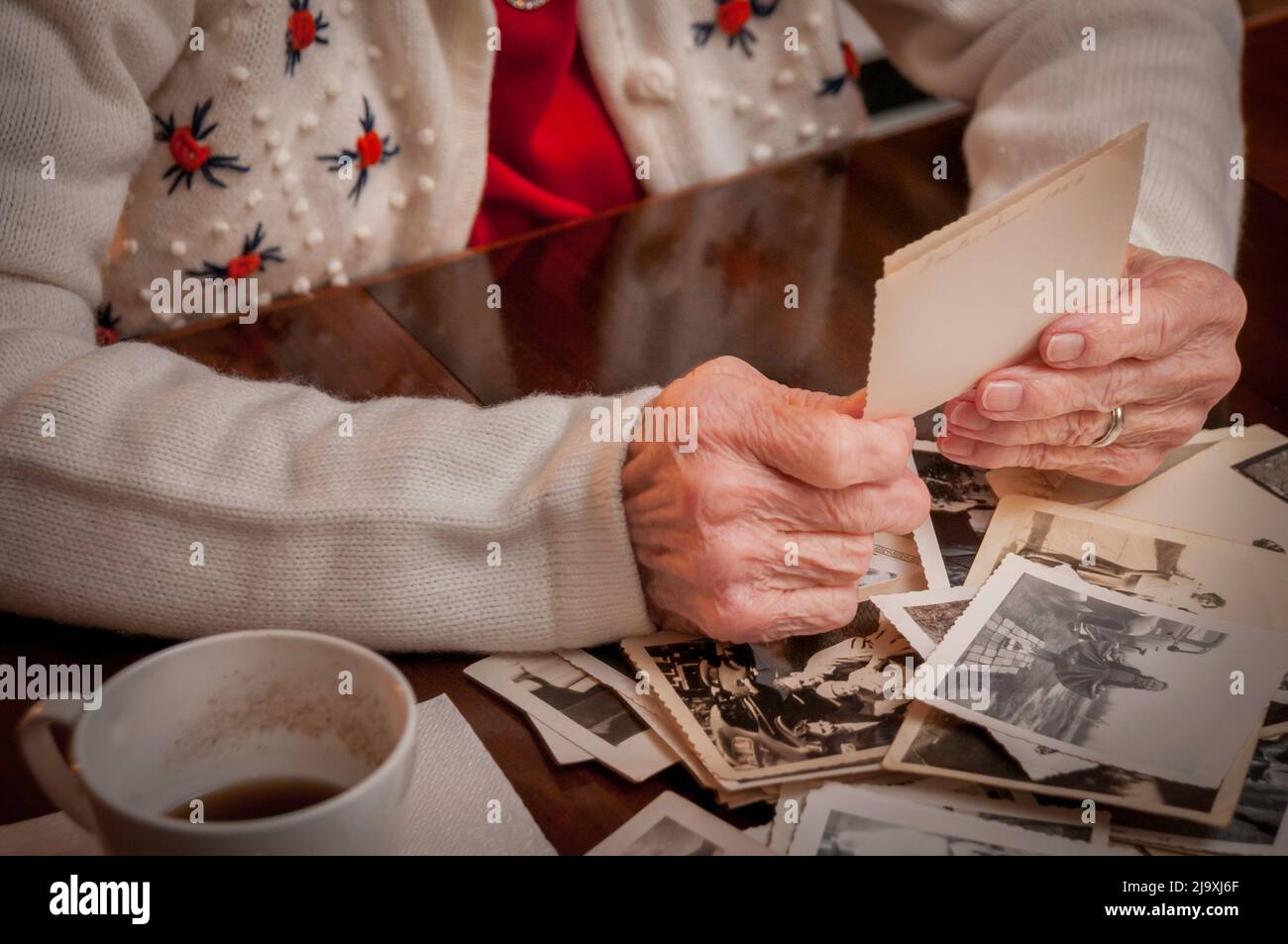 Elderly woman holding an old picture and reminiscing Stock Photo - Alamy