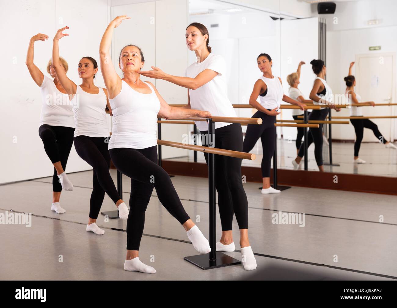 European female ballet teacher showing moves in front of a group of ...
