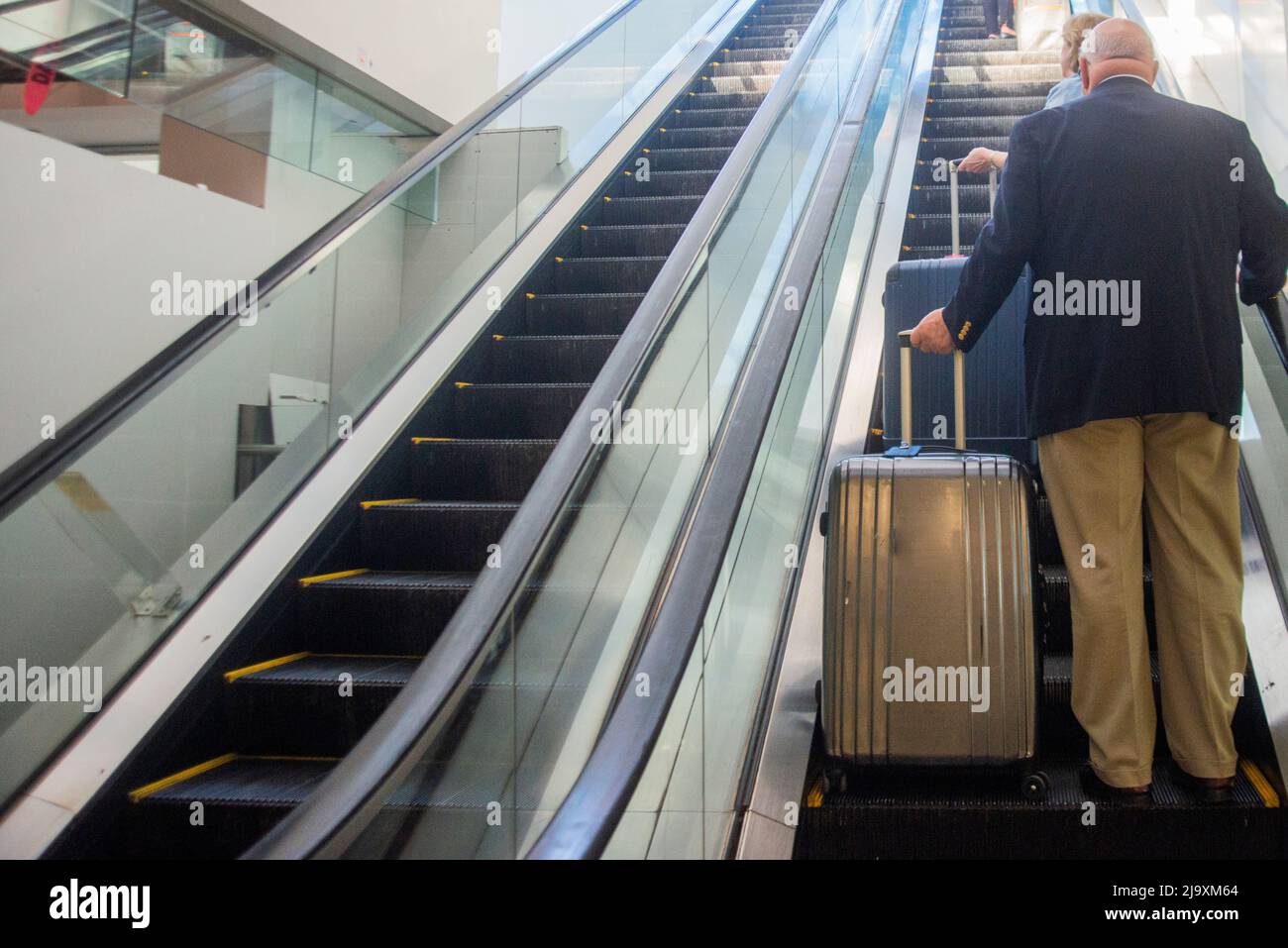 Senior riding escalator at airport Stock Photo - Alamy