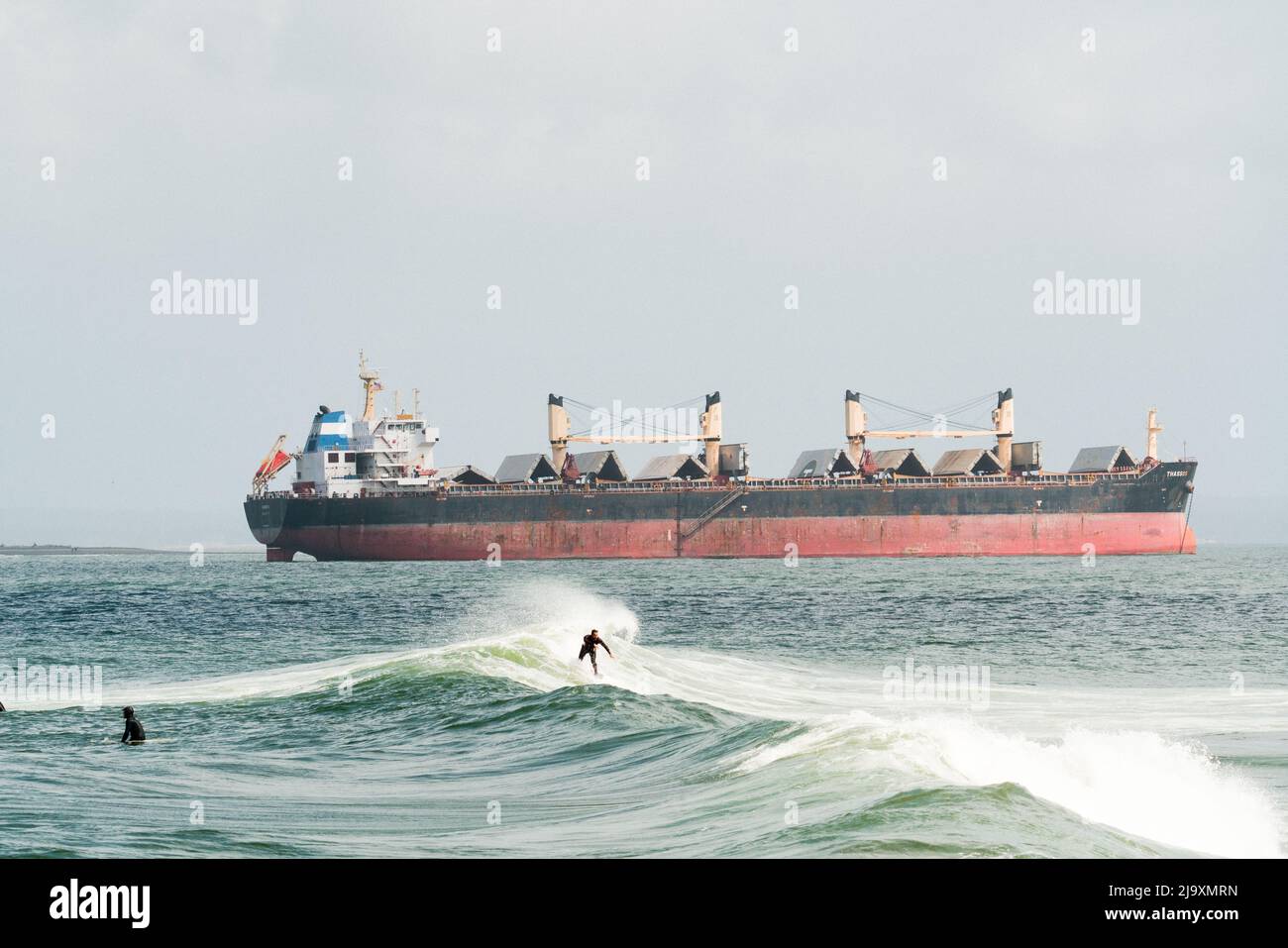 Wide view of a surfer in front of a ship Stock Photo - Alamy