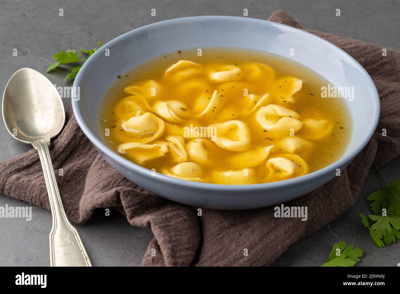 Cappelletti or tortellini brodo soup in a bowl with seasoning over ...