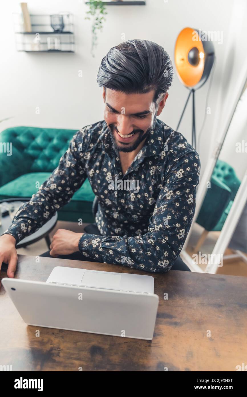 Young Latin American man working from office on his and smiling broadly ...