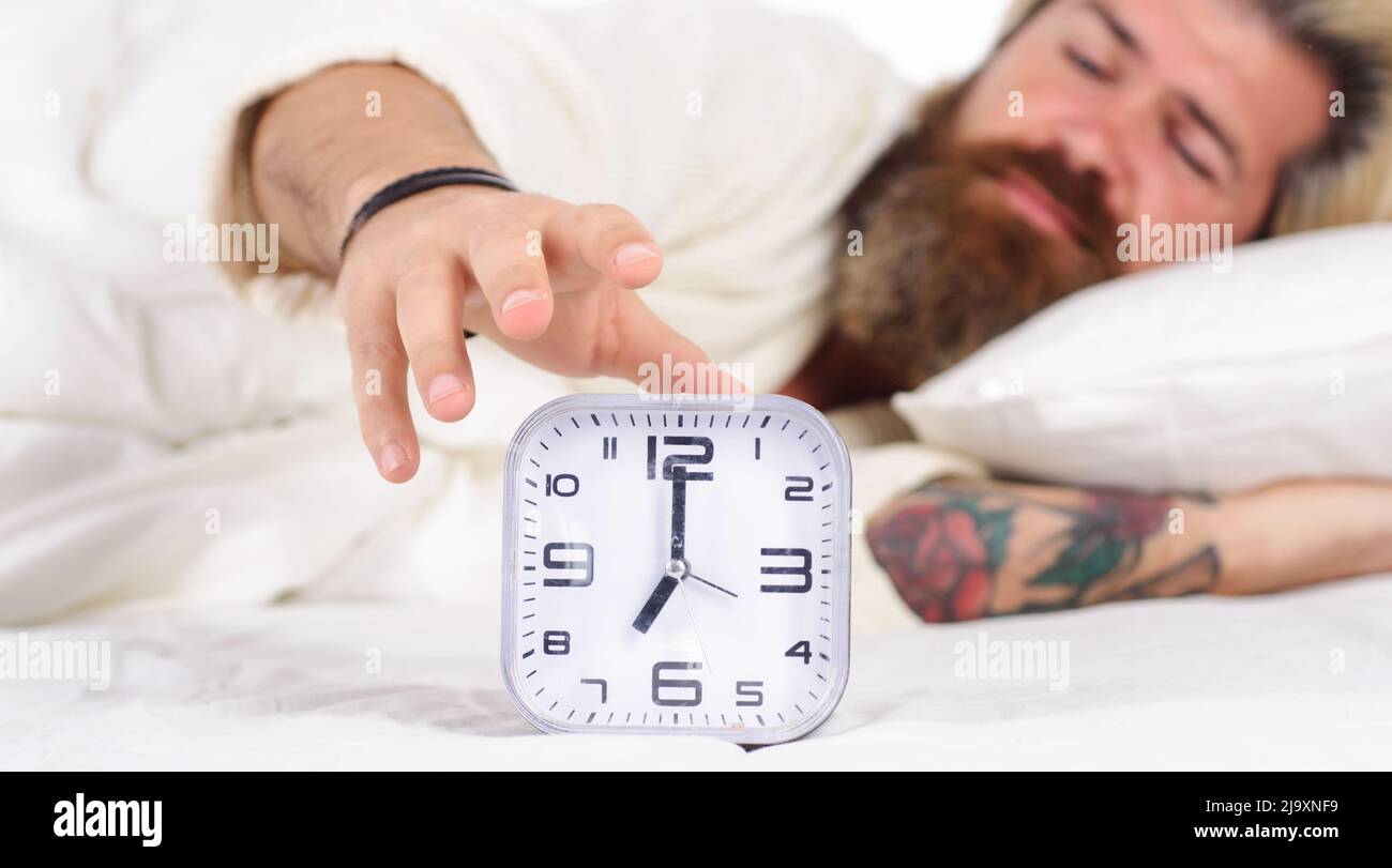 Awaking. Sleepy bearded man turning off alarm clock. Male waking up in ...