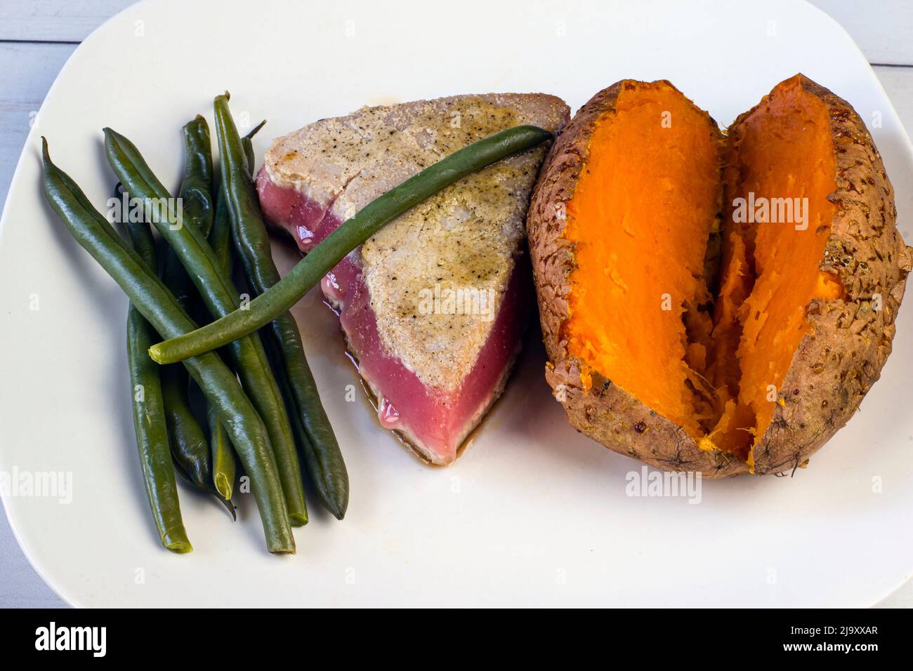 season tuna steak served withsweet potato and green beans Stock Photo ...