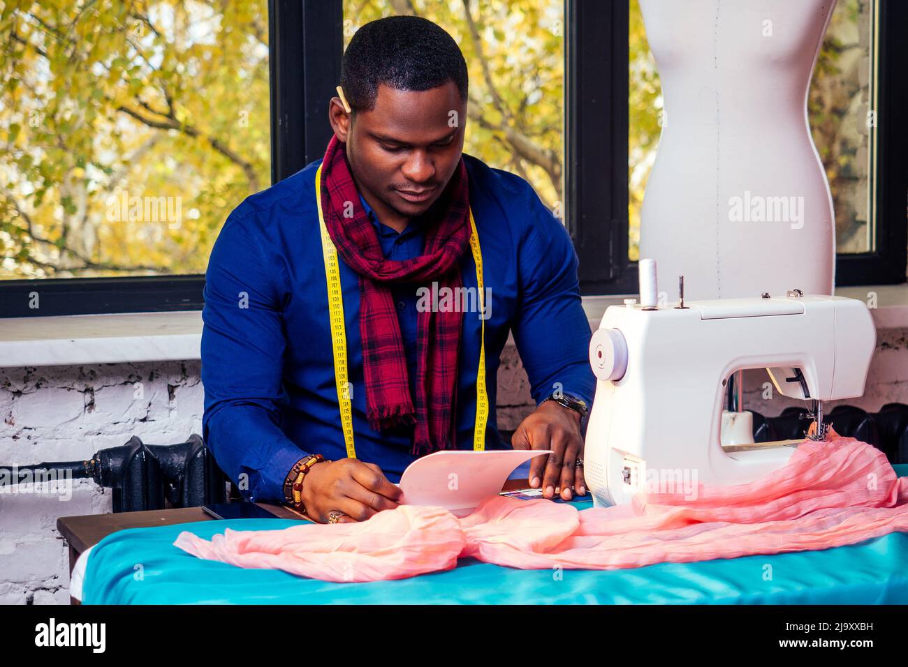 portrait of a handsome african man smiling seamstress with sewing ...