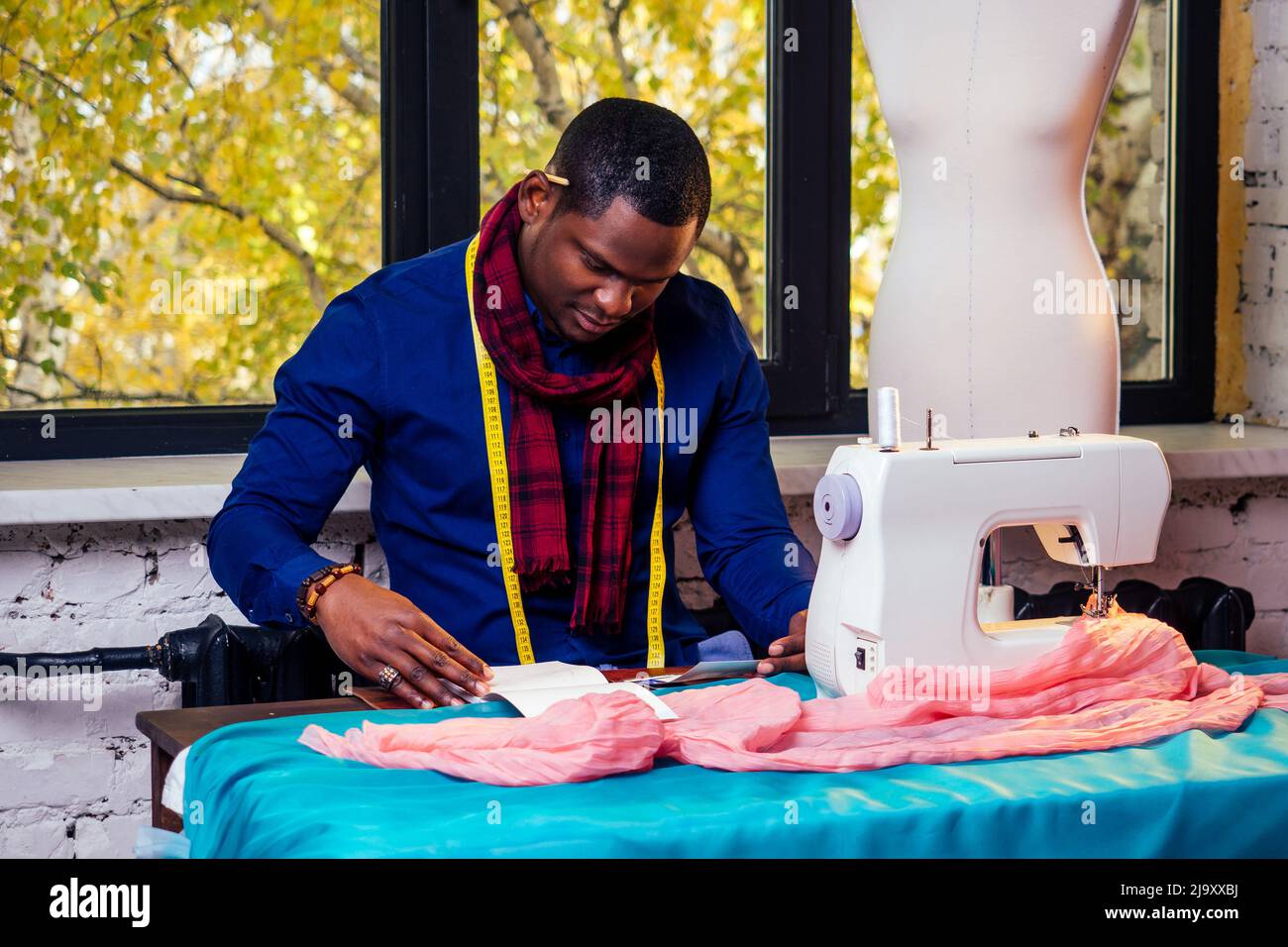 portrait of a handsome african man smiling seamstress with sewing ...
