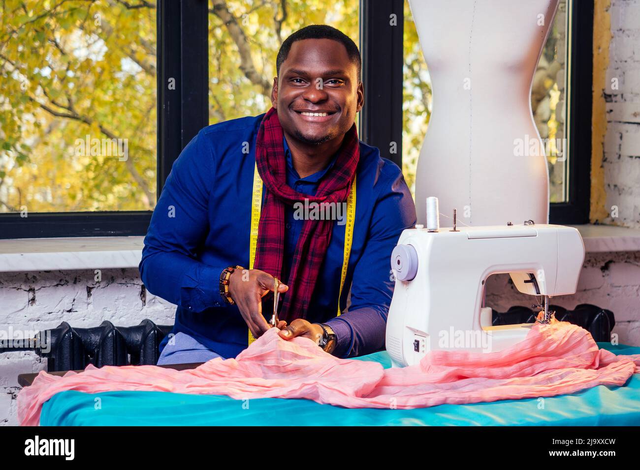 portrait of a handsome african man smiling seamstress with sewing ...