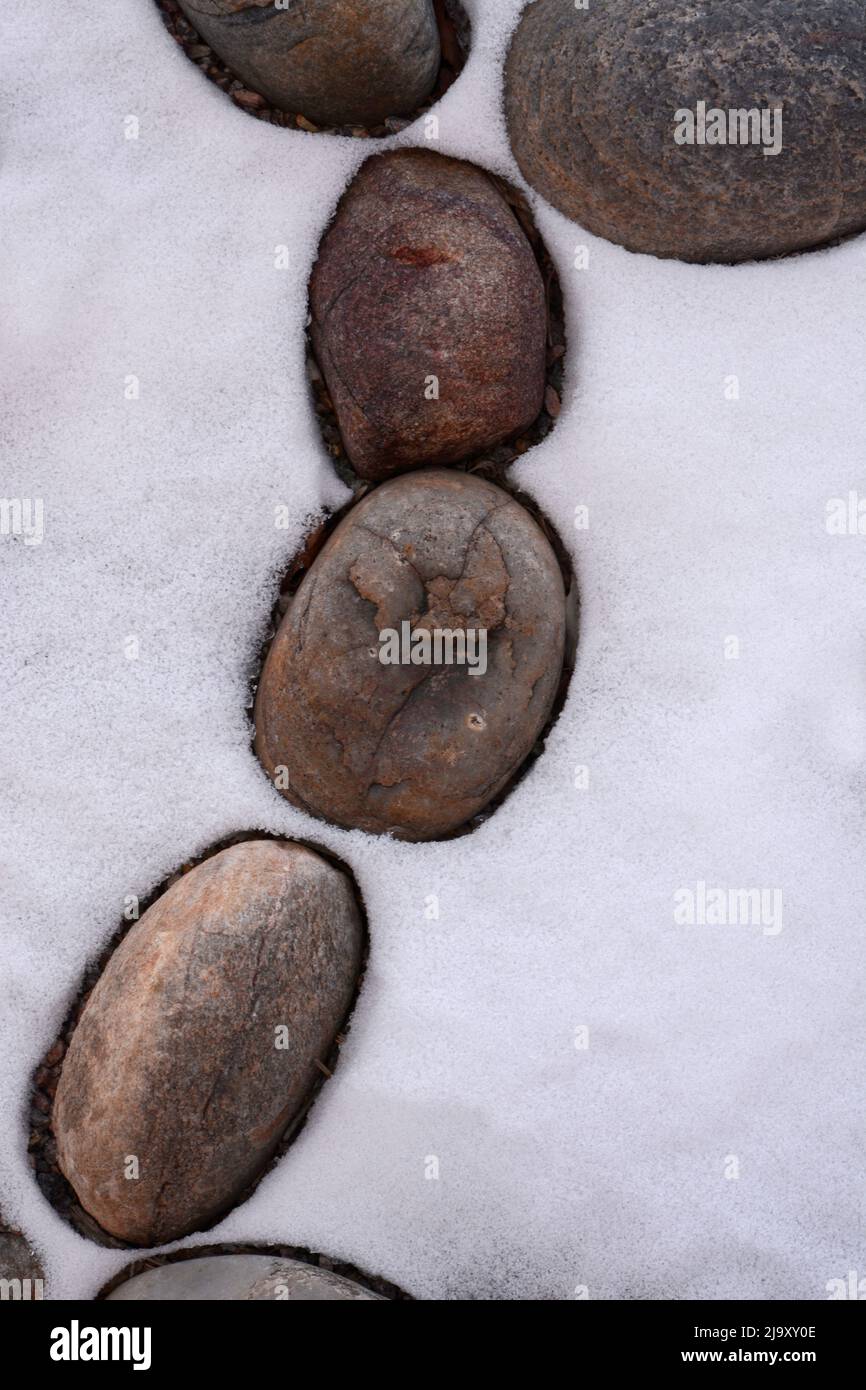 Eroded, round river rocks peek through a light layer of snow Stock ...