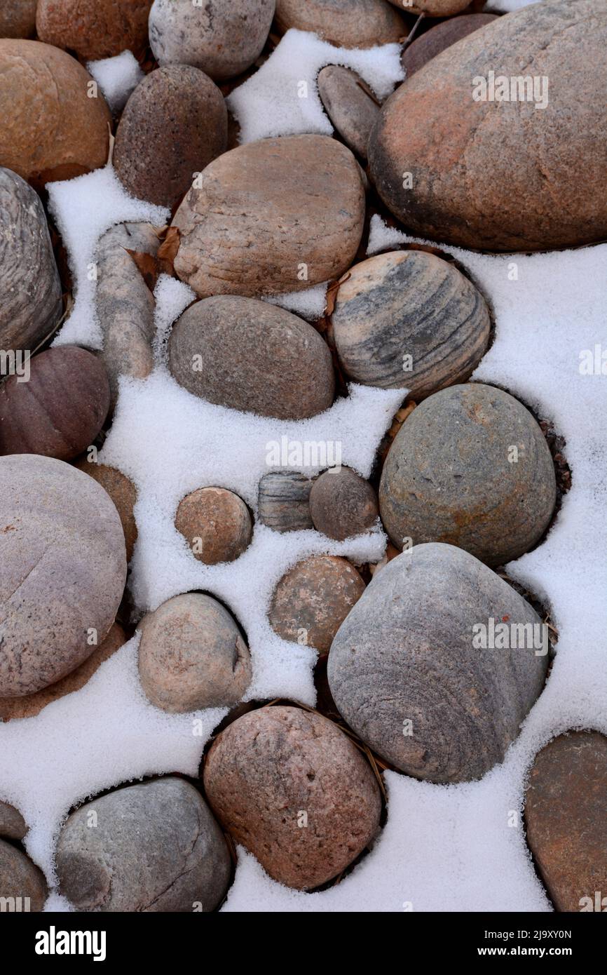 Eroded, round river rocks peek through a light layer of snow Stock ...