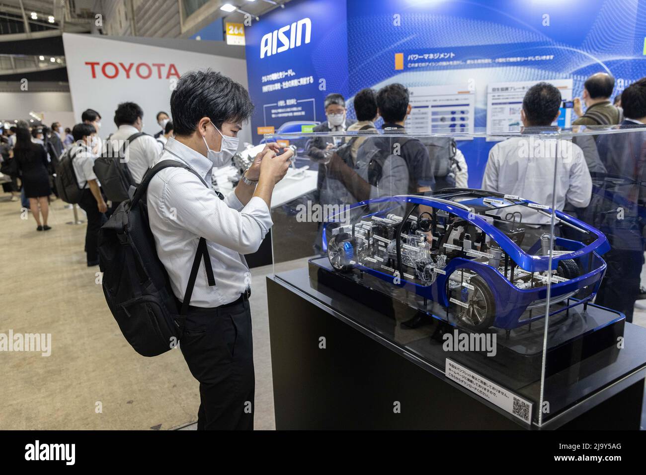 A visitor takes photos of a miniature car model at the exhibitor booth ...