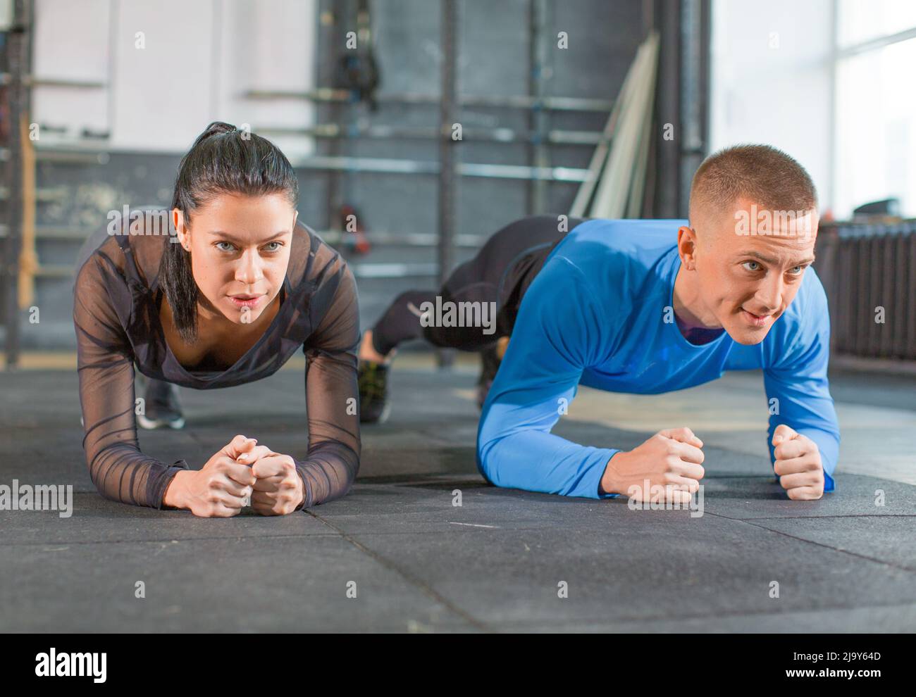 Fitness couple in gym makeing a plank exercise. Close up view of a man ...