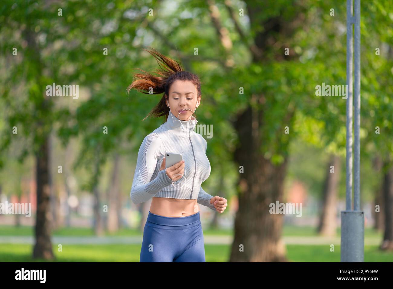 Young woman running in the city park in early morning. Attractive ... Young woman running in the city park in early morning. Attractive ...