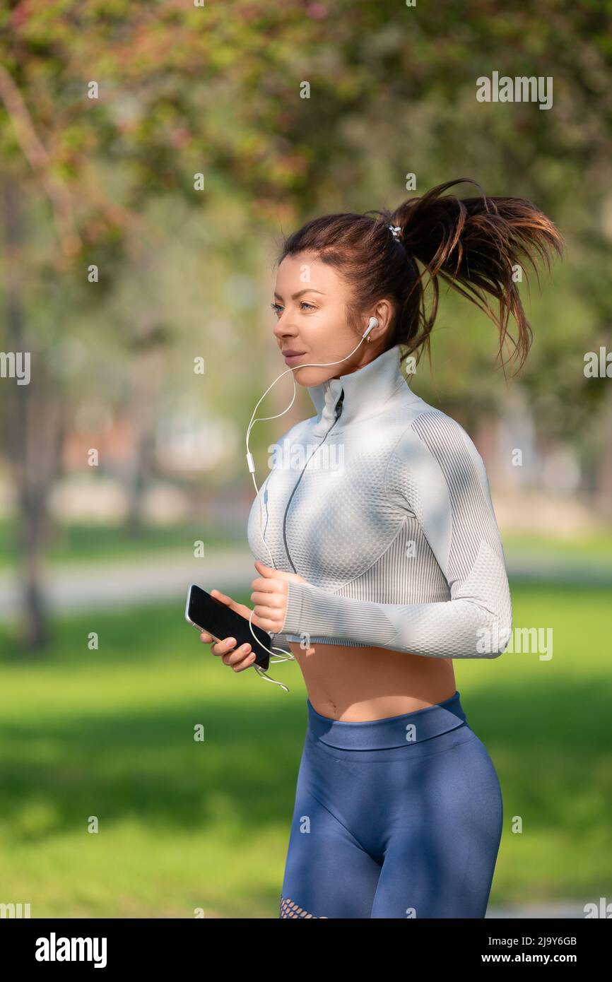 Young woman running in the city park in early morning. Attractive ...