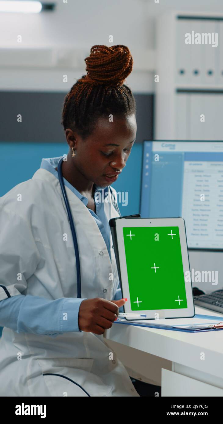 Medic pointing at tablet with green screen and talking to patient for ...
