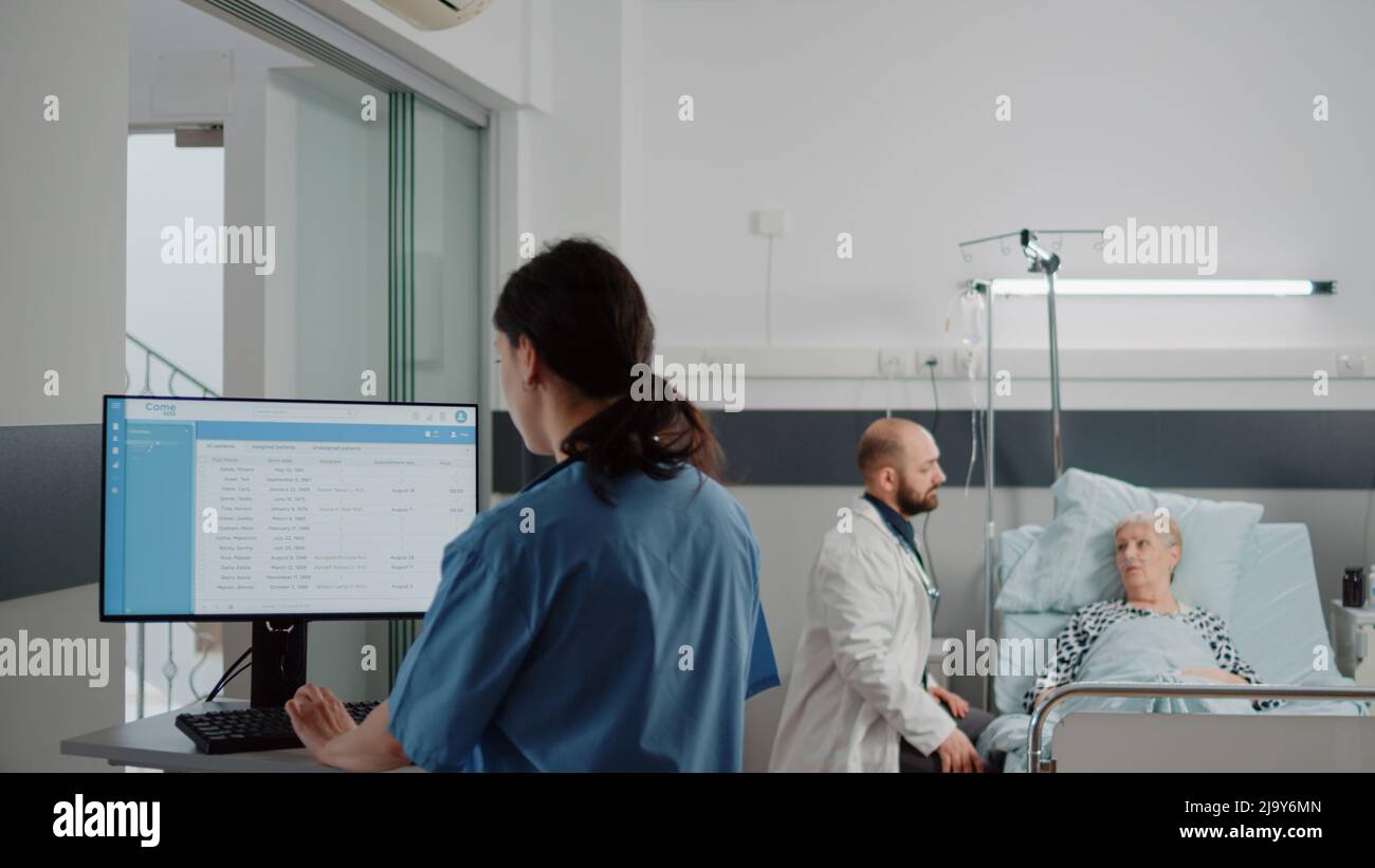 Woman working as nurse and looking at computer with files for ...