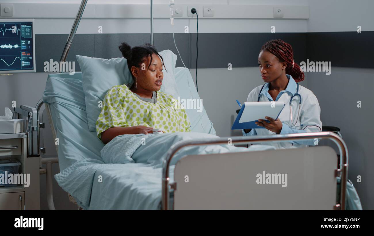 Woman doctor doing healthcare consultation with ill patient in hospital ...