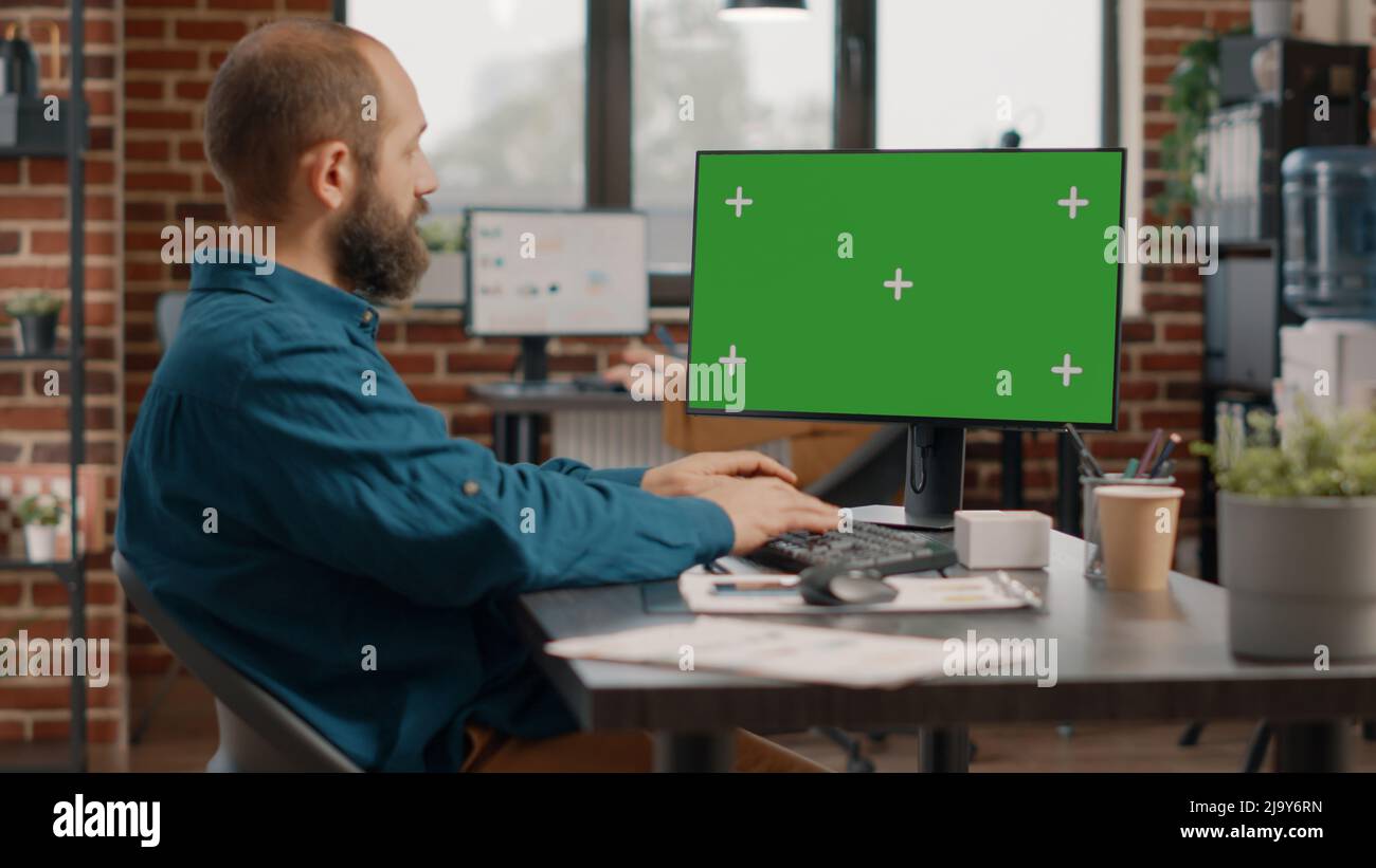 Business man working with horizontal green screen on monitor in office ...
