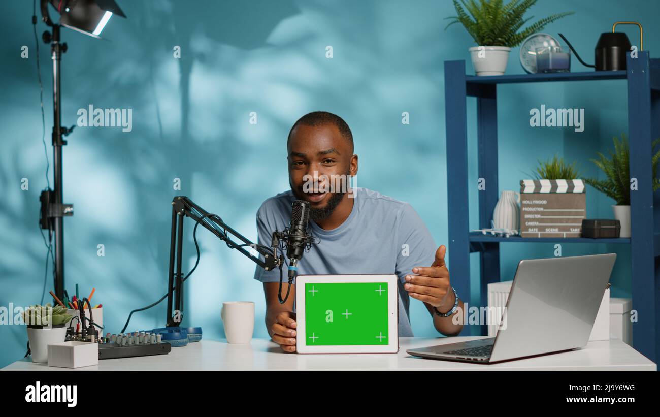 Black vlogger showing tablet with horizontal green screen on camera for ...