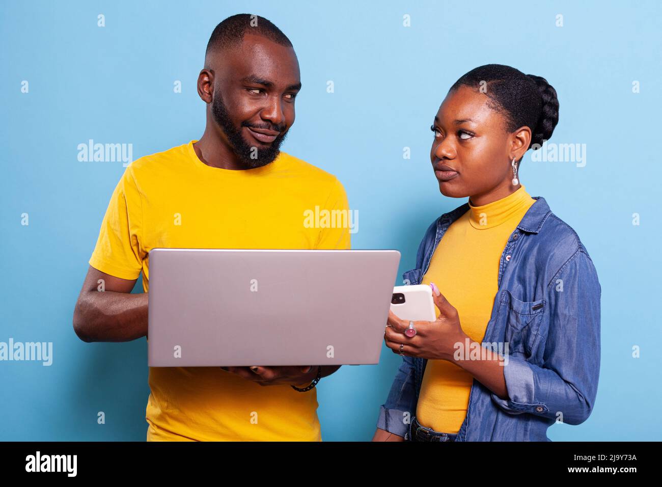 Boyfriend and girlfriend working with computer and mobile phone in ...