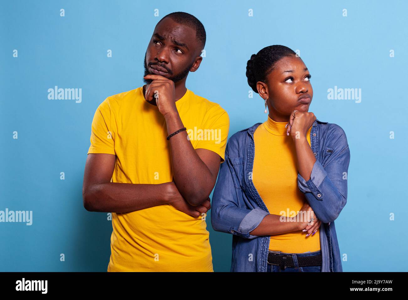 Uncertain couple thinking about clever decision in studio. Pensive and ...