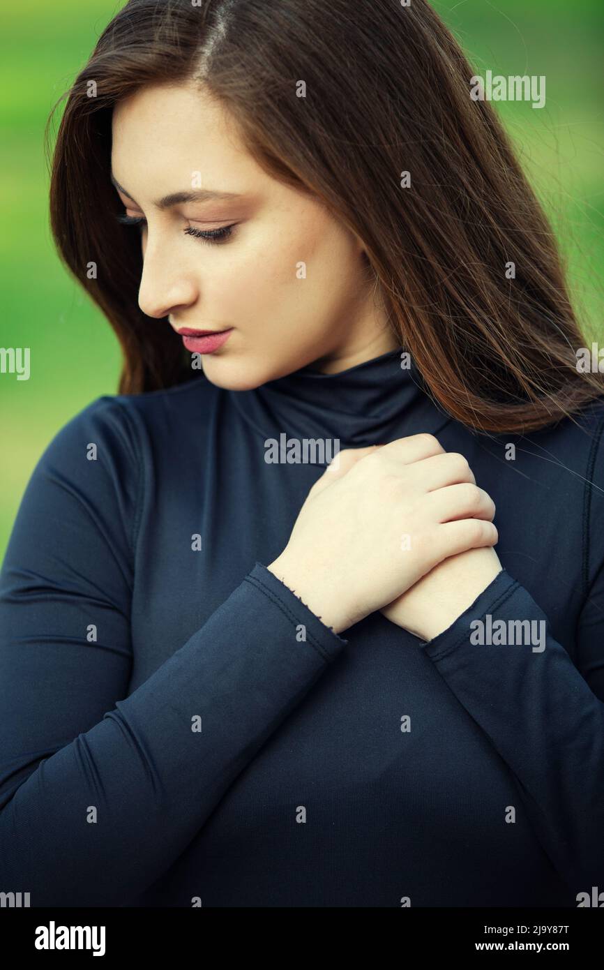 Beautiful woman hands over heart looking down Stock Photo - Alamy