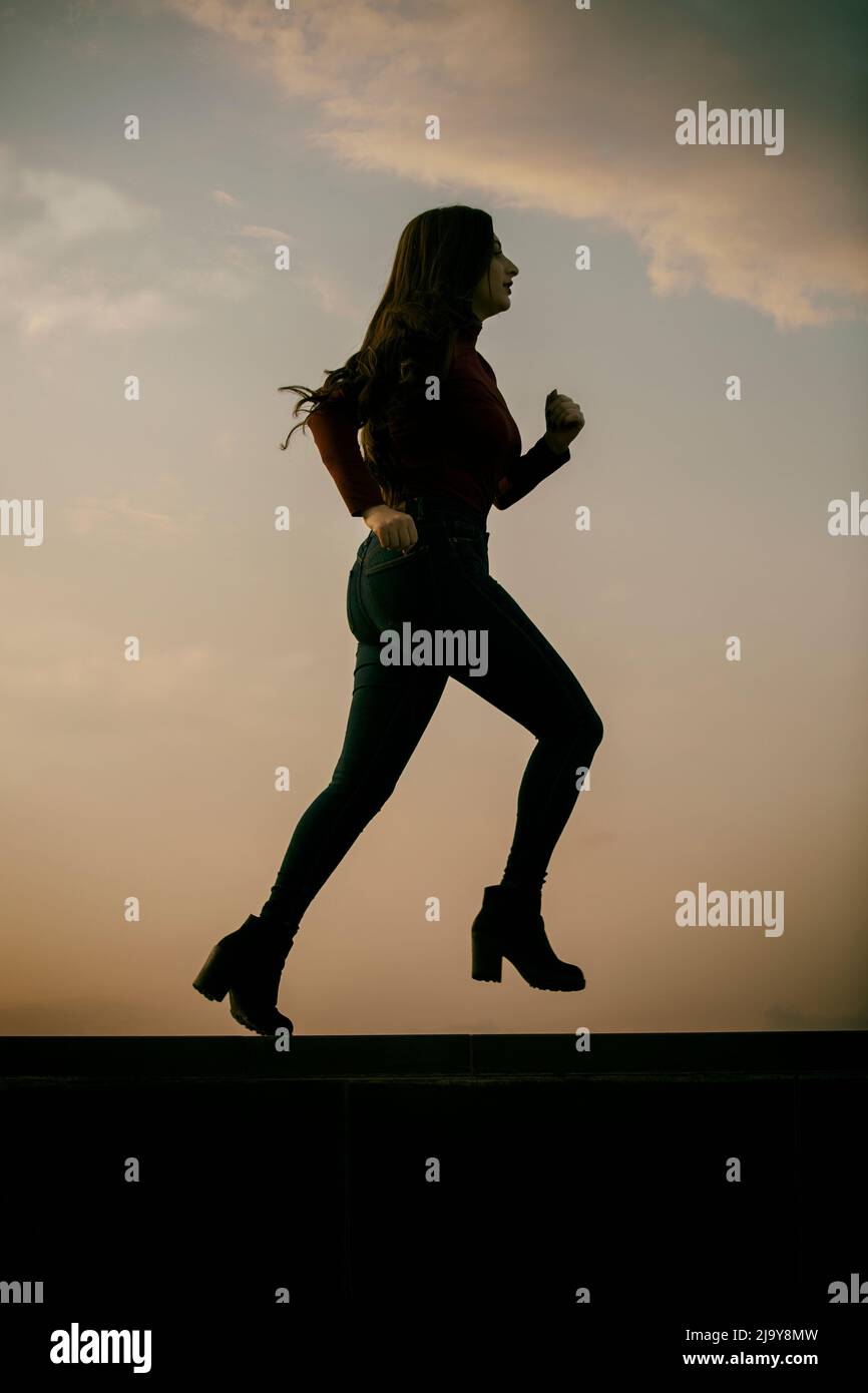 Woman running away at sunset Stock Photo - Alamy