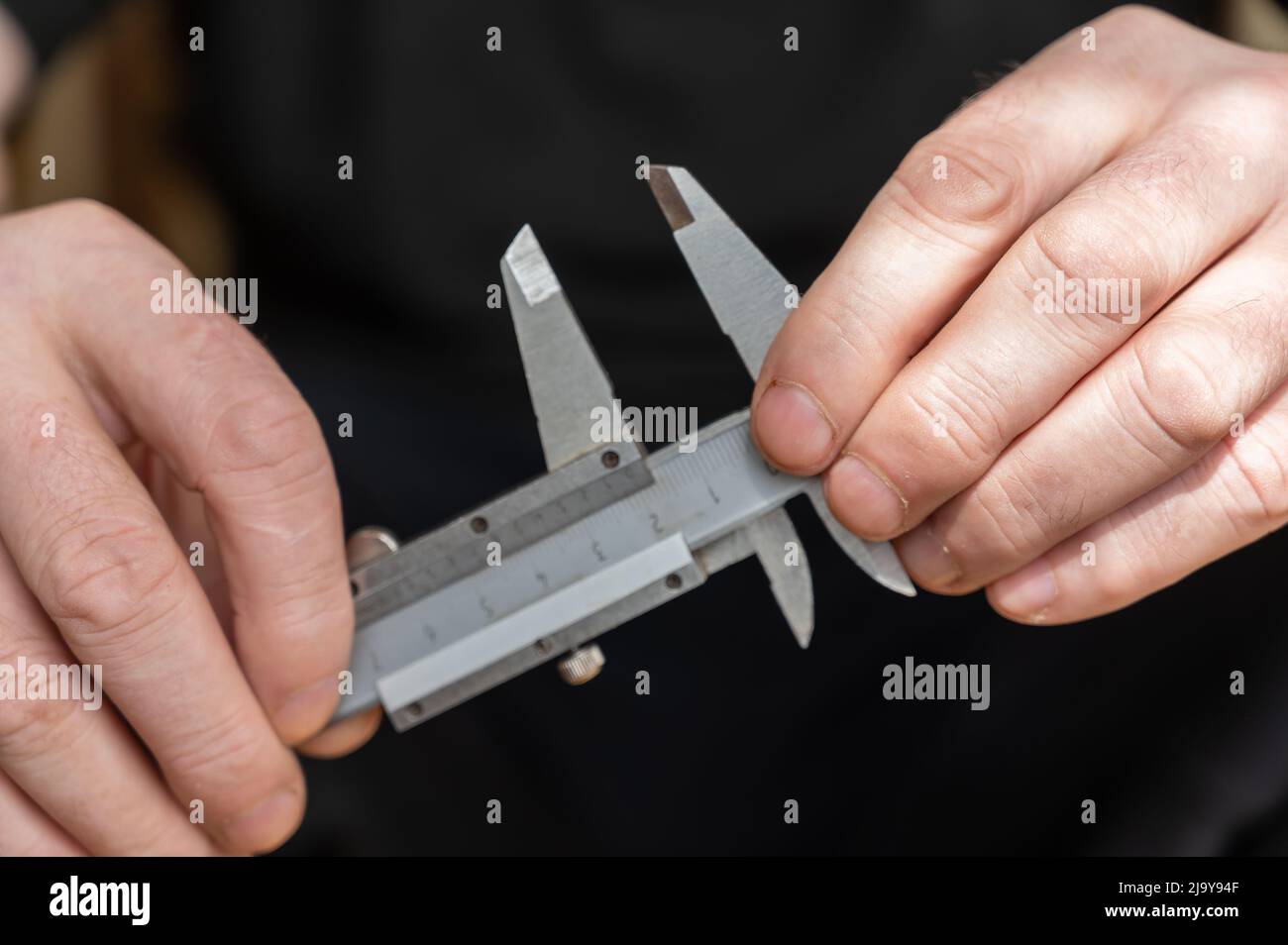 A man's hand holding a caliper. An adult man with a high-precision ...