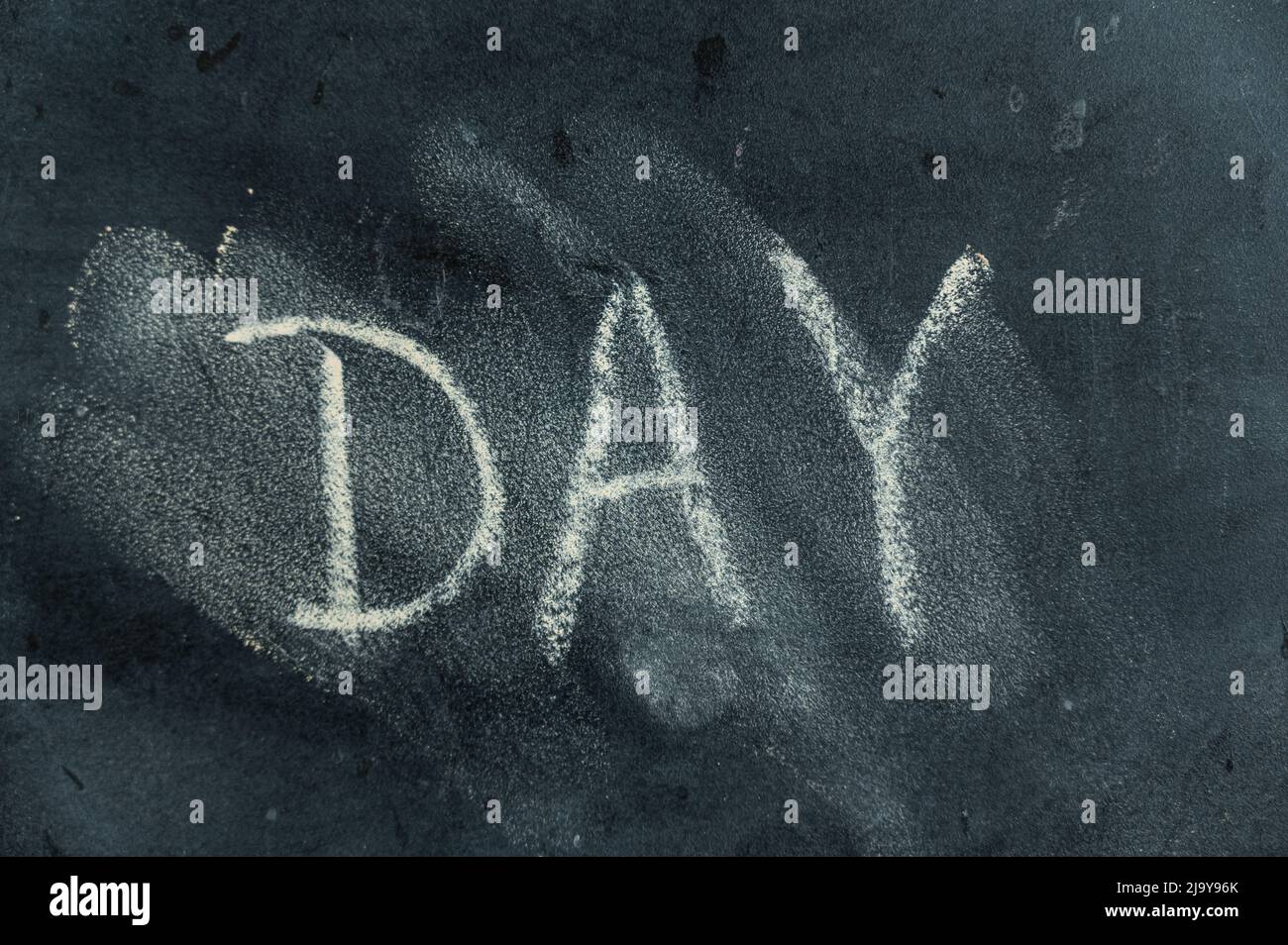 Semi-erased word DAY on black chalkboard. Handwritten word. Fuzzy ...