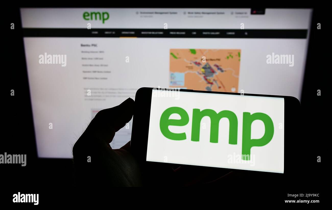 Person holding mobile phone with logo of company PT Energi Mega Persada ...