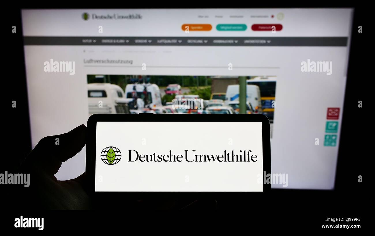 Person holding mobile phone with logo of association Deutsche ...