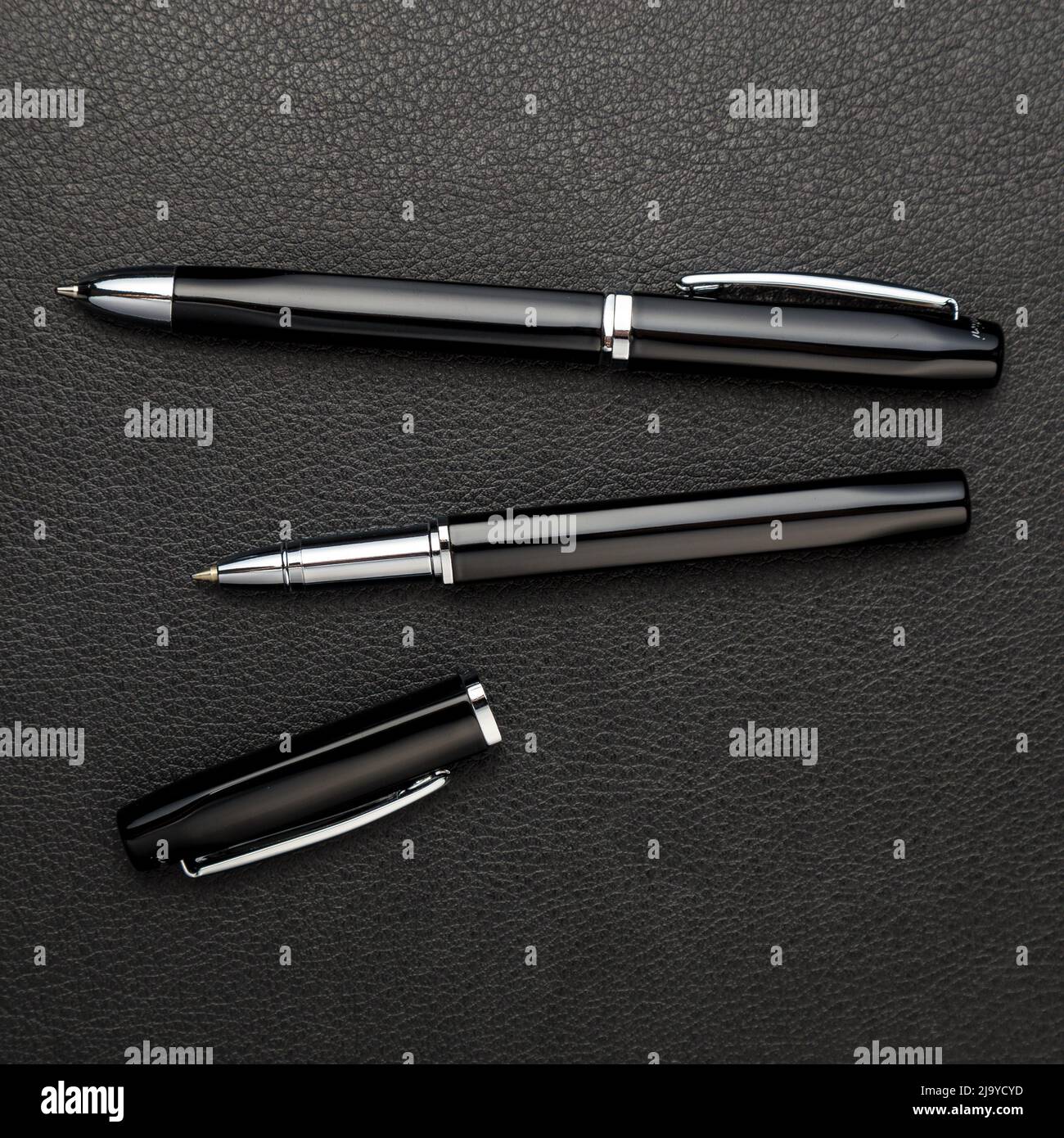 Pens lying on black leather background with copy space Stock Photo - Alamy