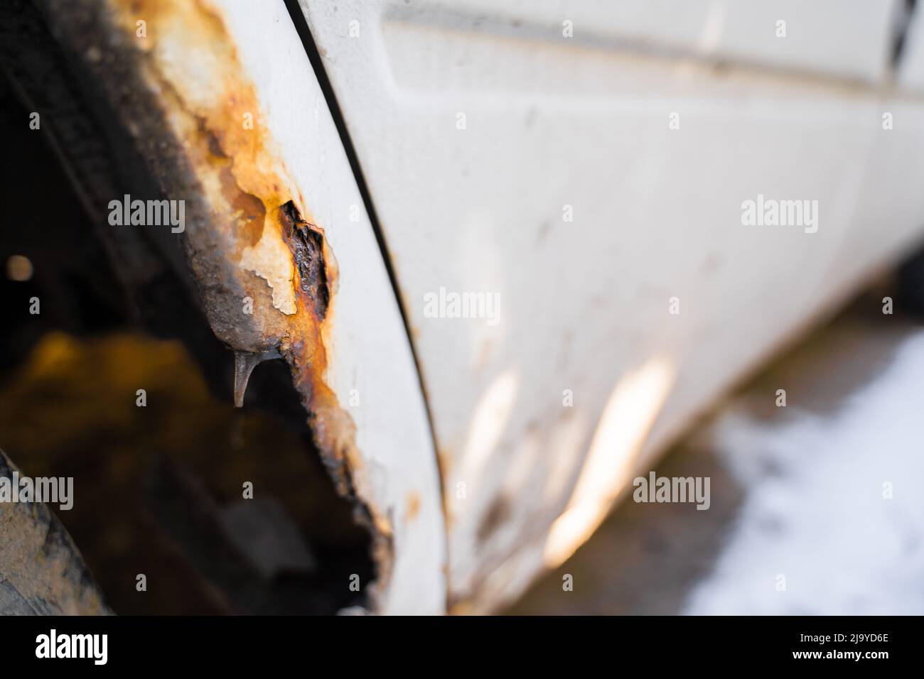 Rusted fender of a white car close-up. The effect of reagents in winter ...