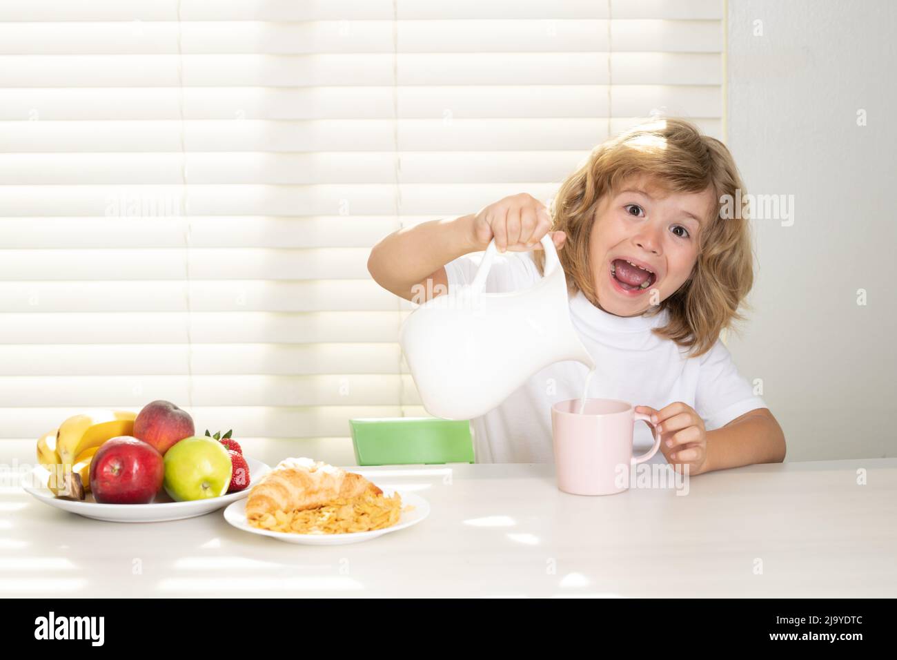Fuuny excited little boy pouring whole cows milk for breakfast ...