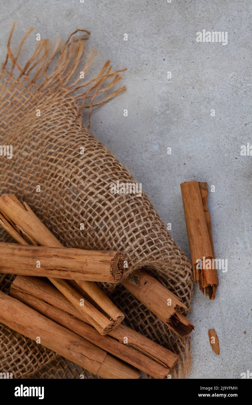 Whole cinnamon sticks on mottled grey surface with burlap and copy ...