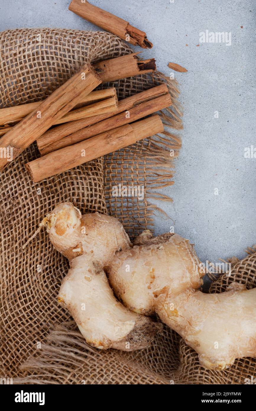 Whole cinnamon sticks and ginger root on mottled grey surface with ...
