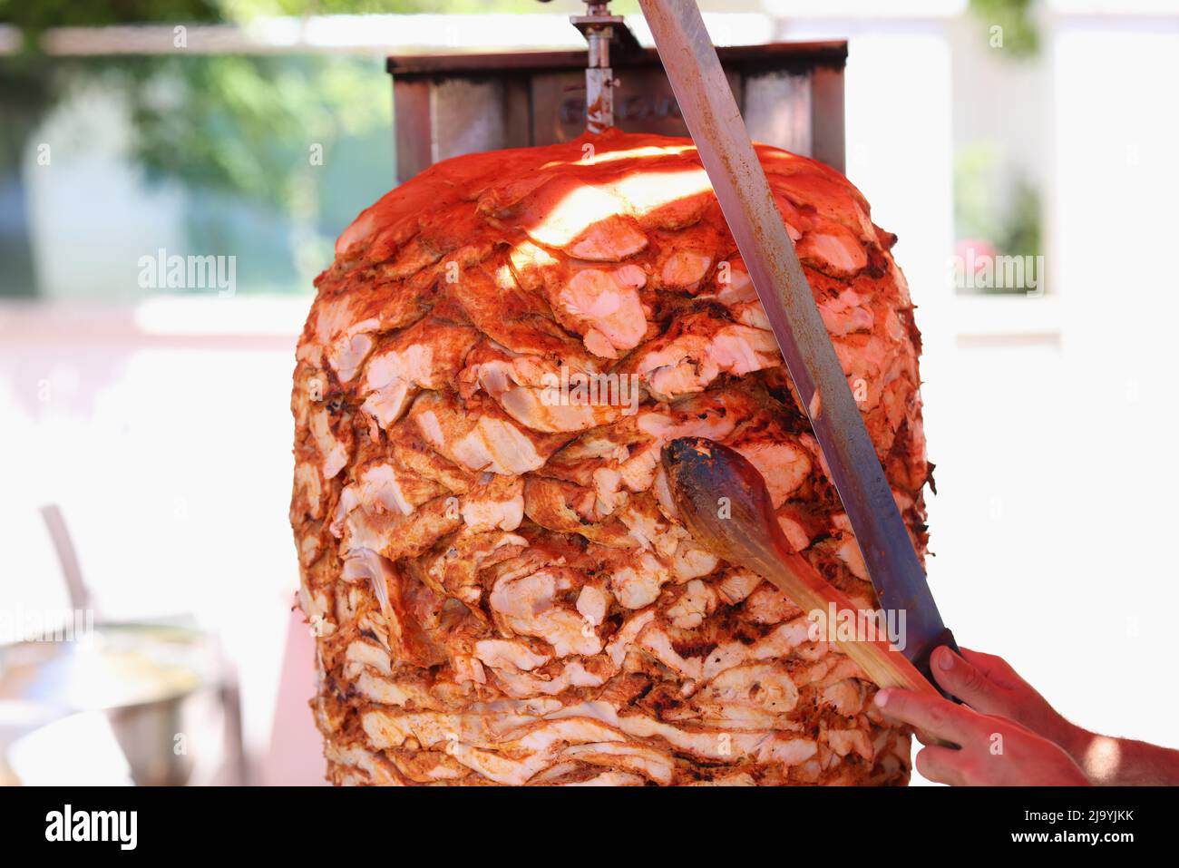 Chef cuts grilled chicken meat from rotating spit and prepares ...