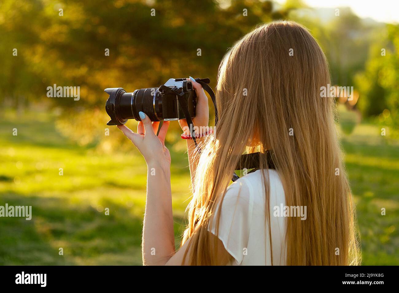portrait of professional female photographer in the park photographing ...