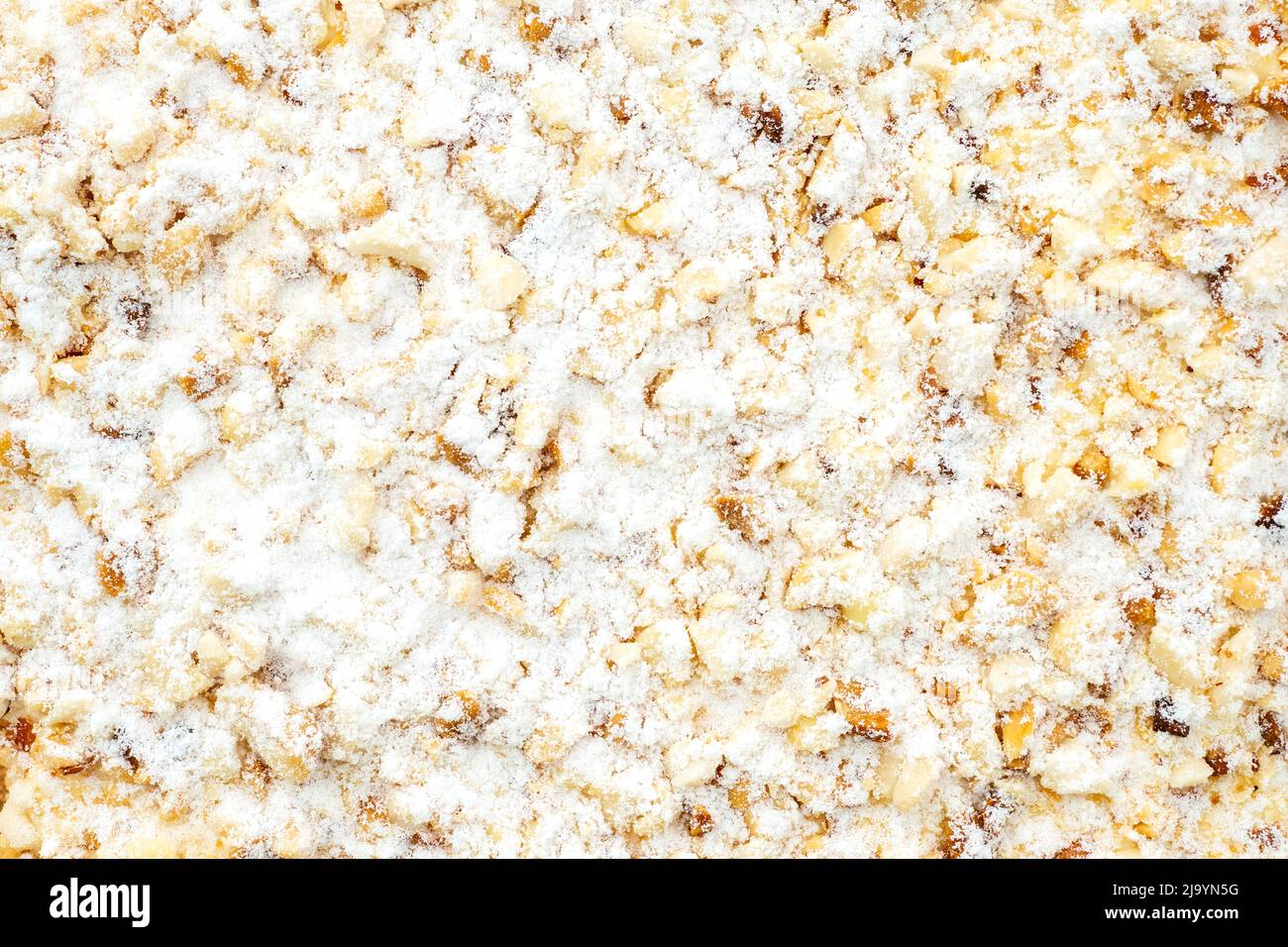 Part of sweet cake with white powder, cream and broken nuts, top view ...