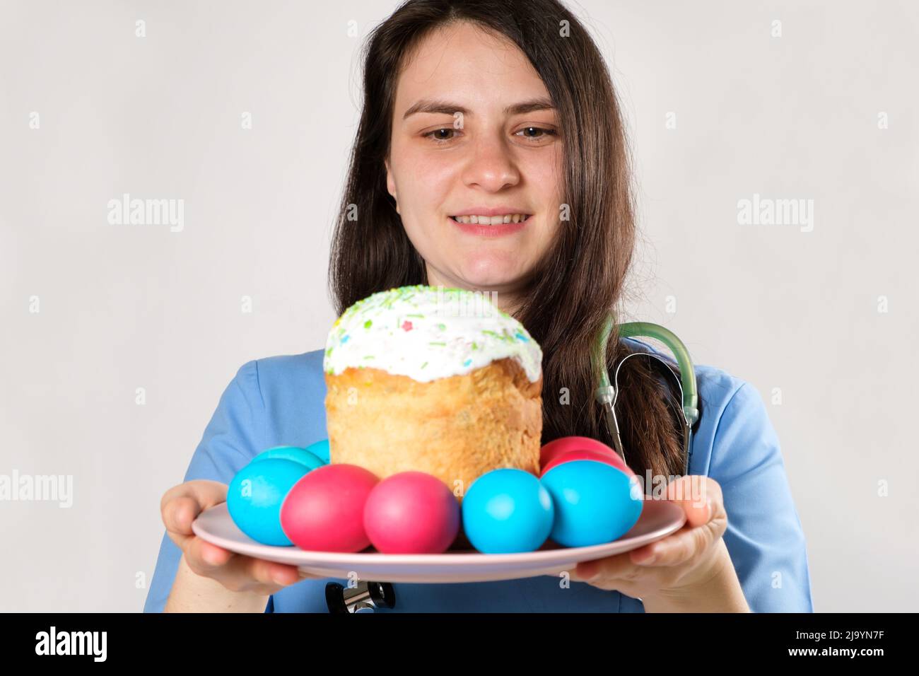 The doctor holds an Easter cake and painted eggs and smiles on a white ...