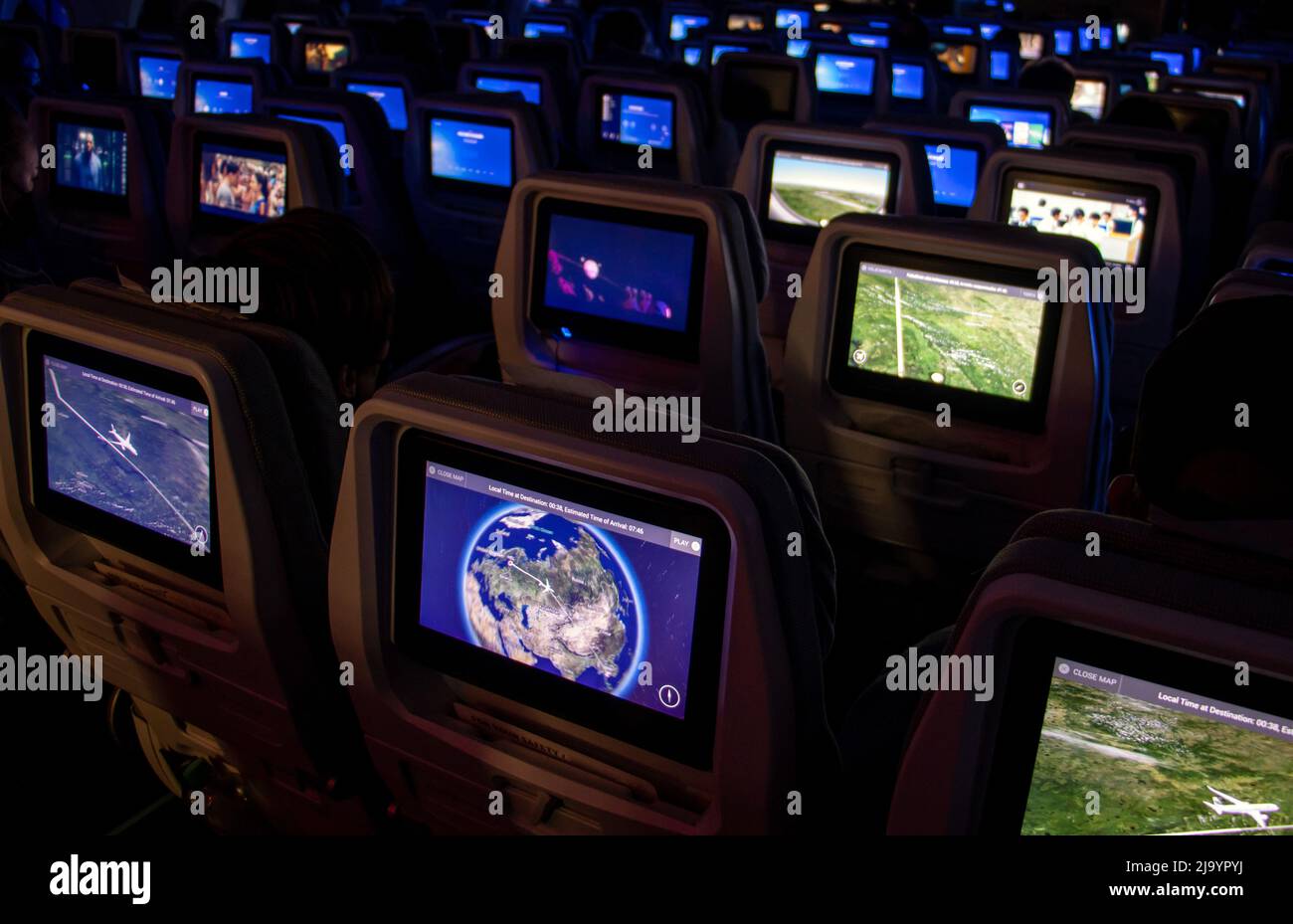 Interior of an flying aircraft with monitors on the seats, at a night ...