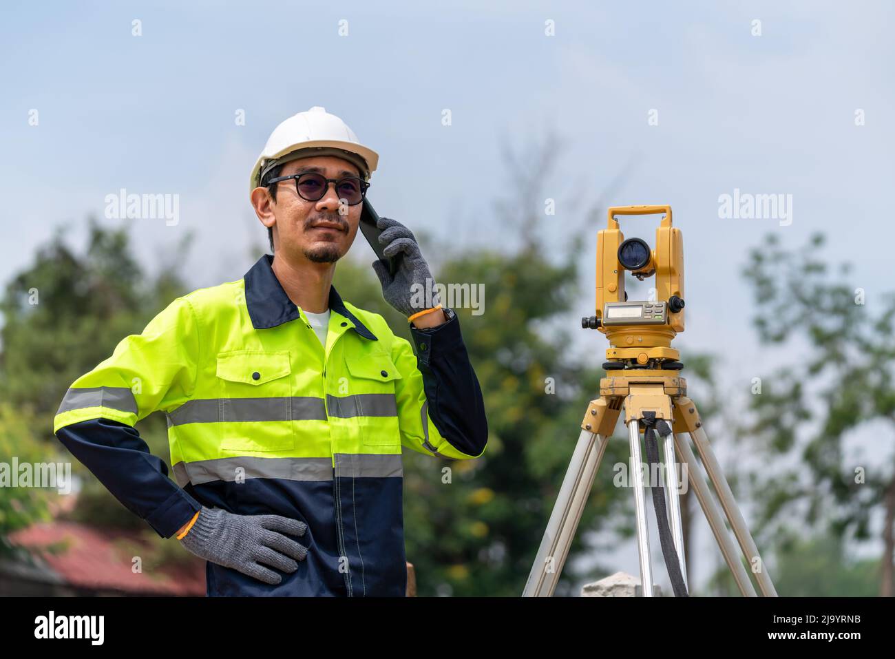 Surveyor Civil Engineer using the phone with equipment theodolite or ...